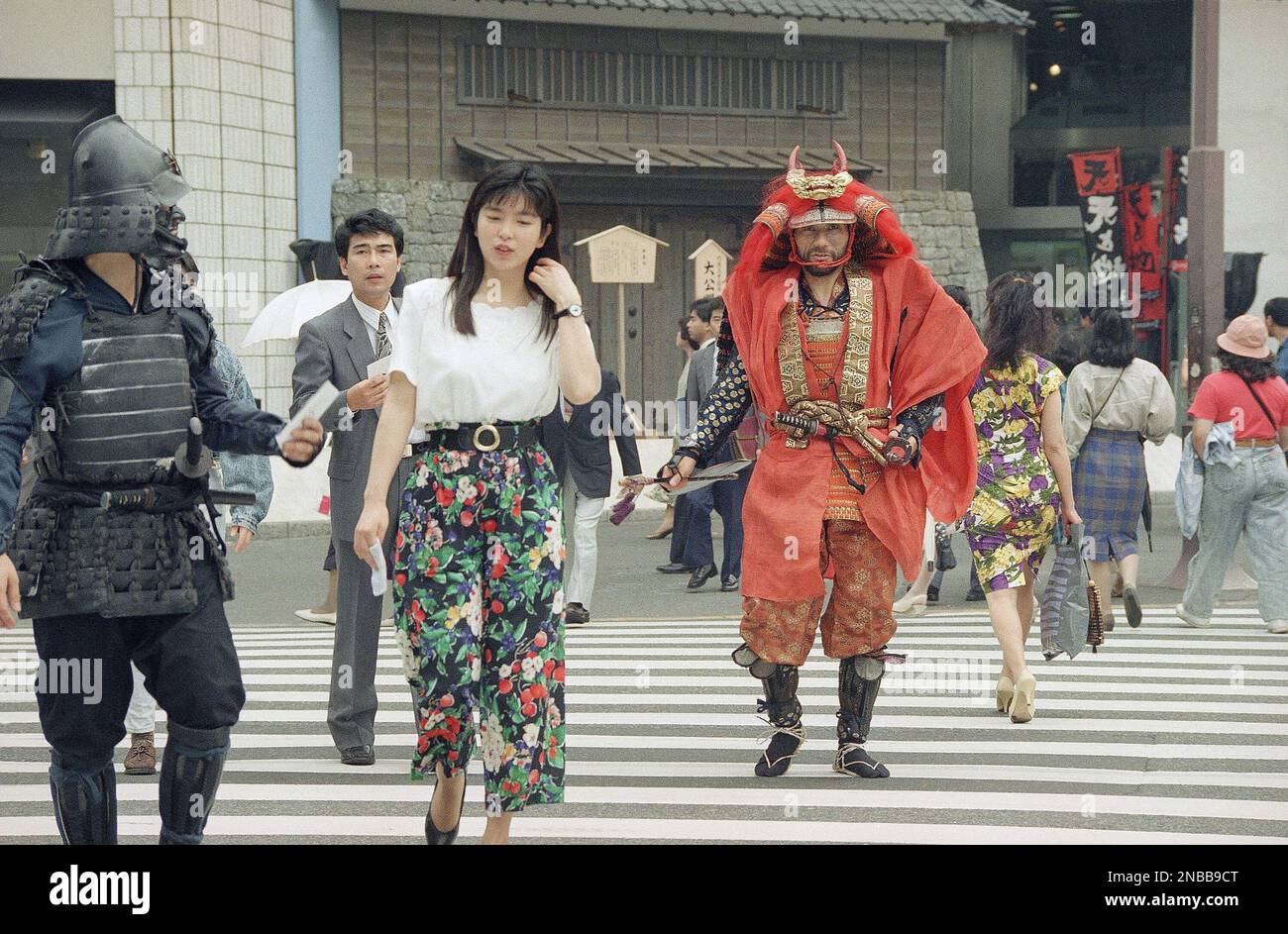 A samurai warrior, fully geared up for battle, walks across a street in ...