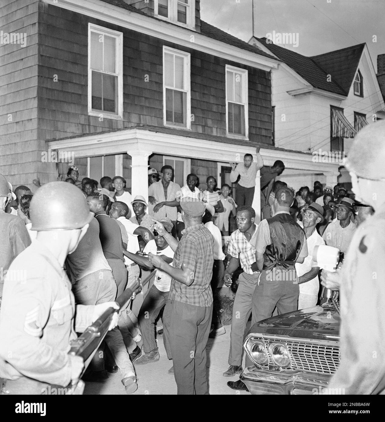 A crowd yells at National Guardsmen drawn up across a street in the ...