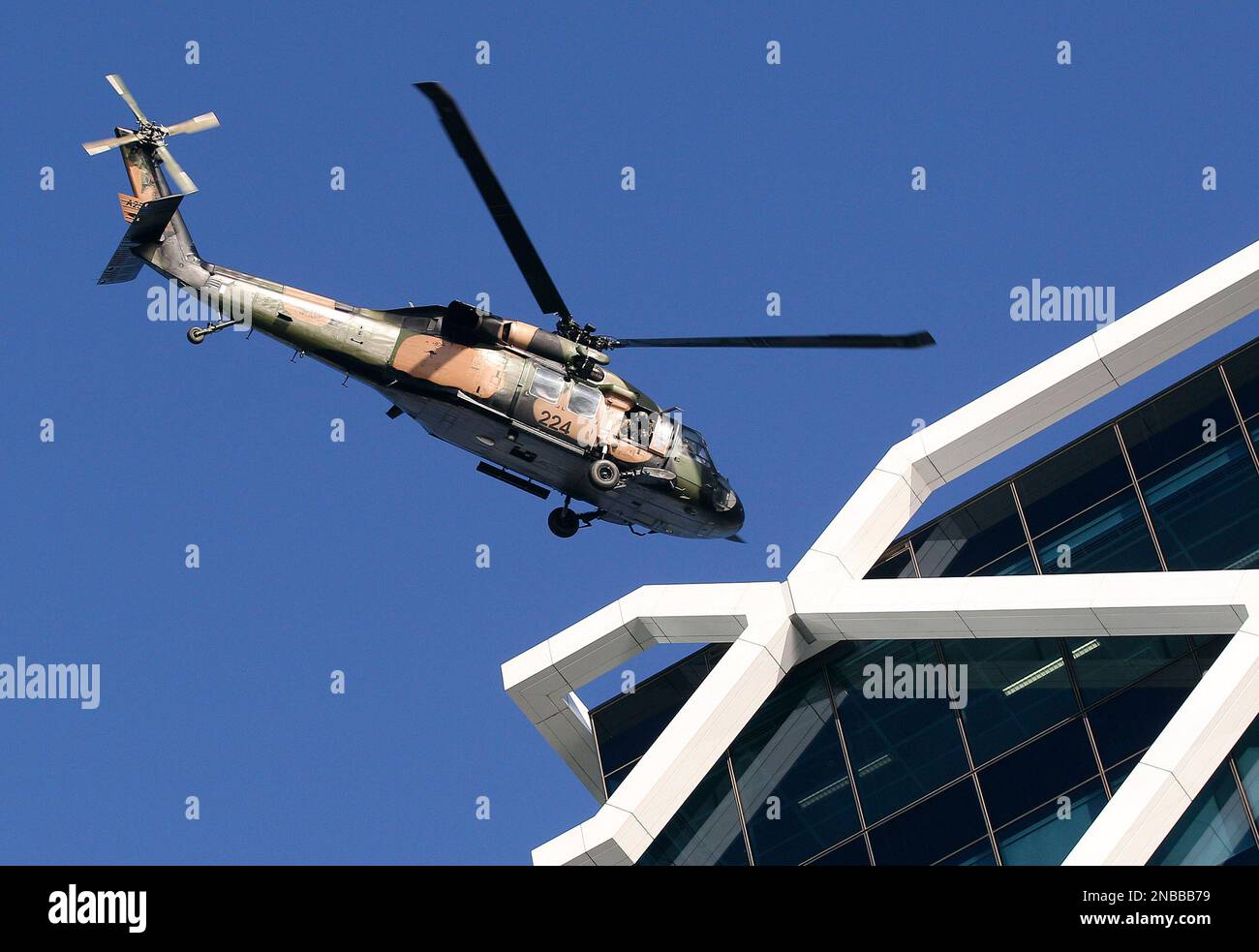 An Australian Army Blackhawk helicopter maneuvers between buildings ...