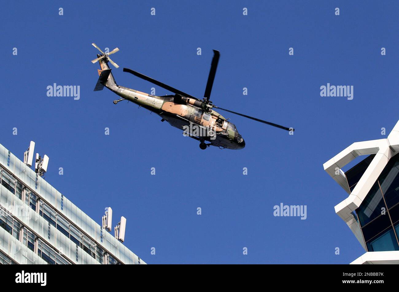 An Australian Army Blackhawk helicopter maneuvers between buildings ...