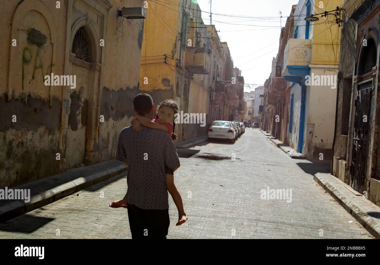 A libyan man with his daughter walks along an empty street in downtown Tripoli, Libya, Tuesday ...