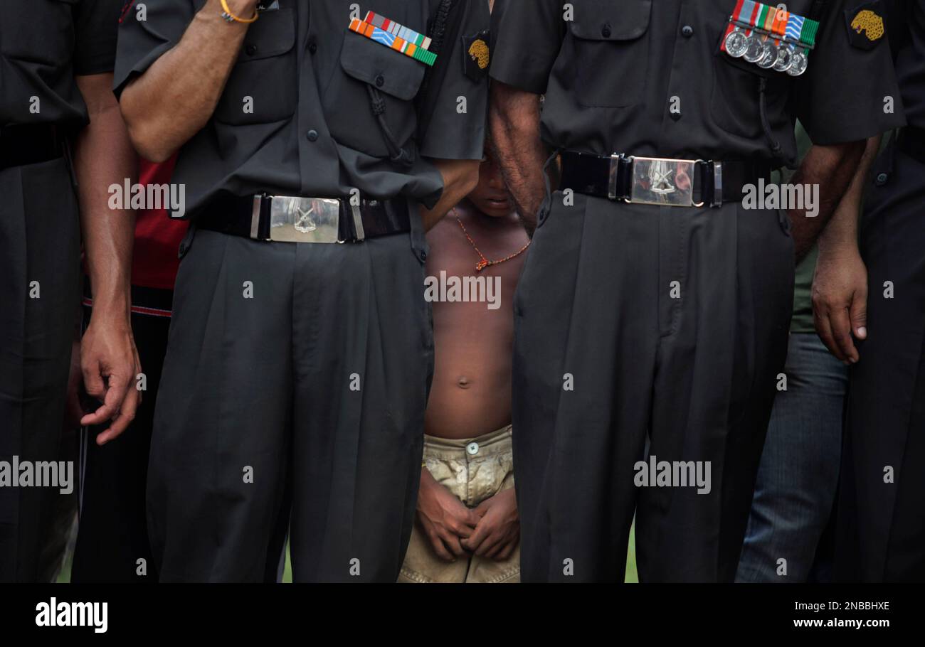 A young Indian boy peeps from behind Indian soldiers as they watch the ...