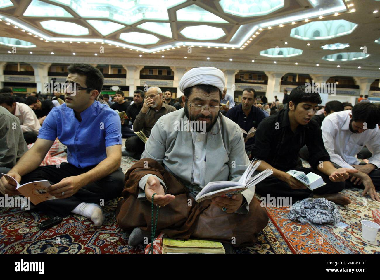 In front of other worshippers, an Iranian clergyman prays in a ...