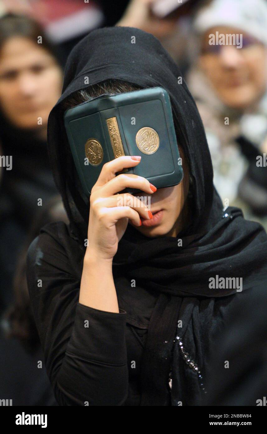 An Iranian woman places the Quran, Islam's holy book, on her forehead ...