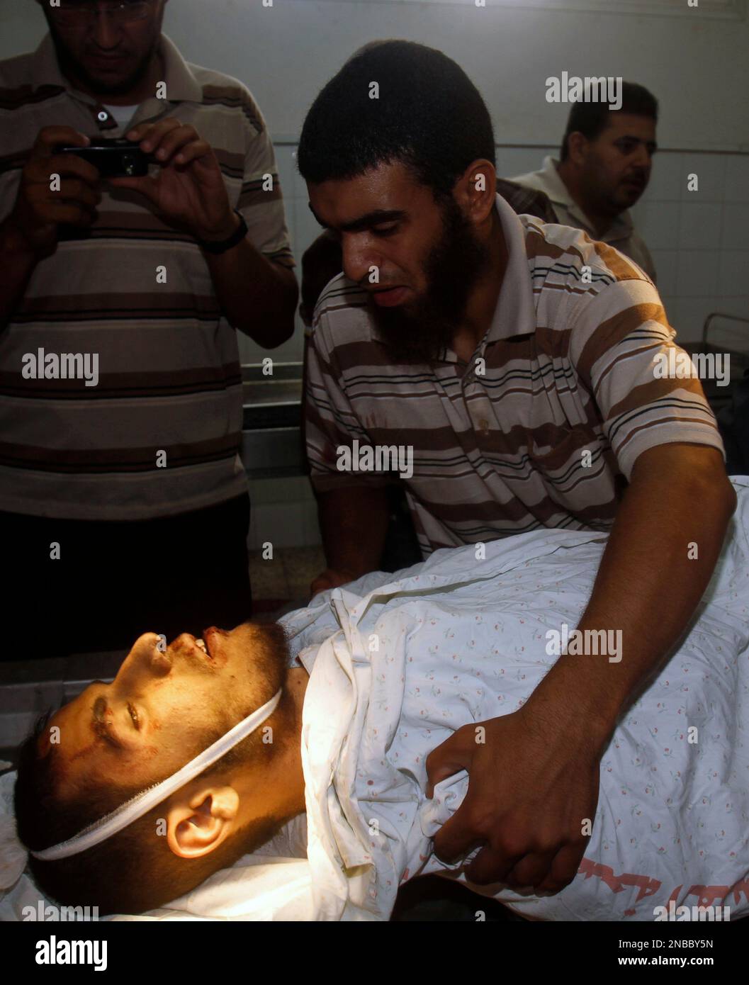 A Palestinian man holds the body of militant Mohammed Enayah, 23, at ...