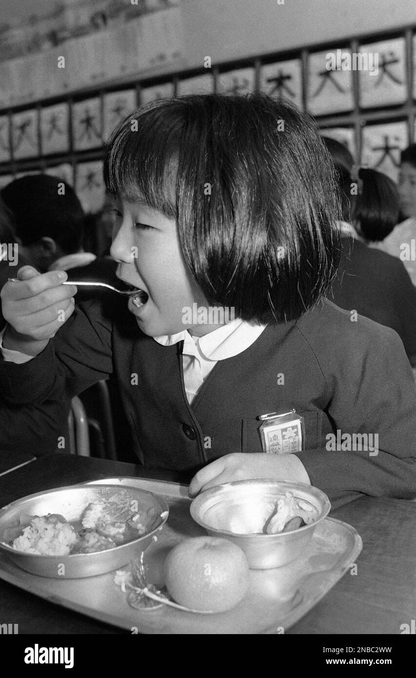 A Tokyo grade school student devours her curried stew and rice lunch ...