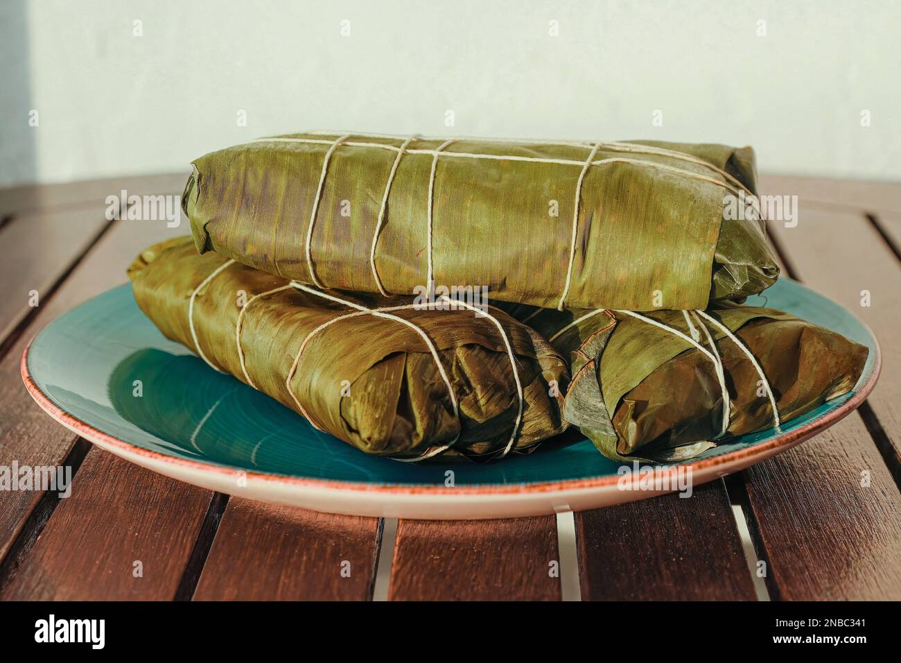 Wrapped Hallaca or Tamale over a rustic table and a blue dish, Mexican ...