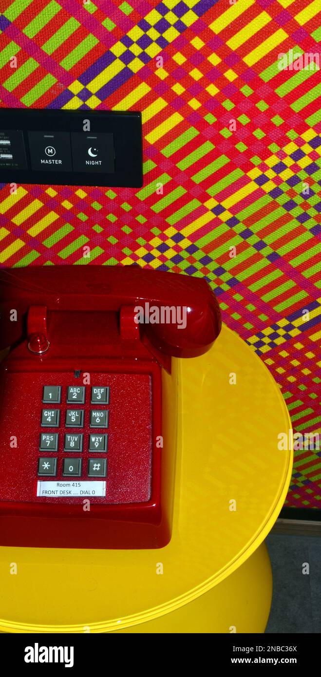 A bright red telephone or phone with push buttons on a bright yellow ...
