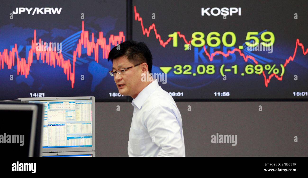 A currency trader stands near the screens showing the Korea Composite ...