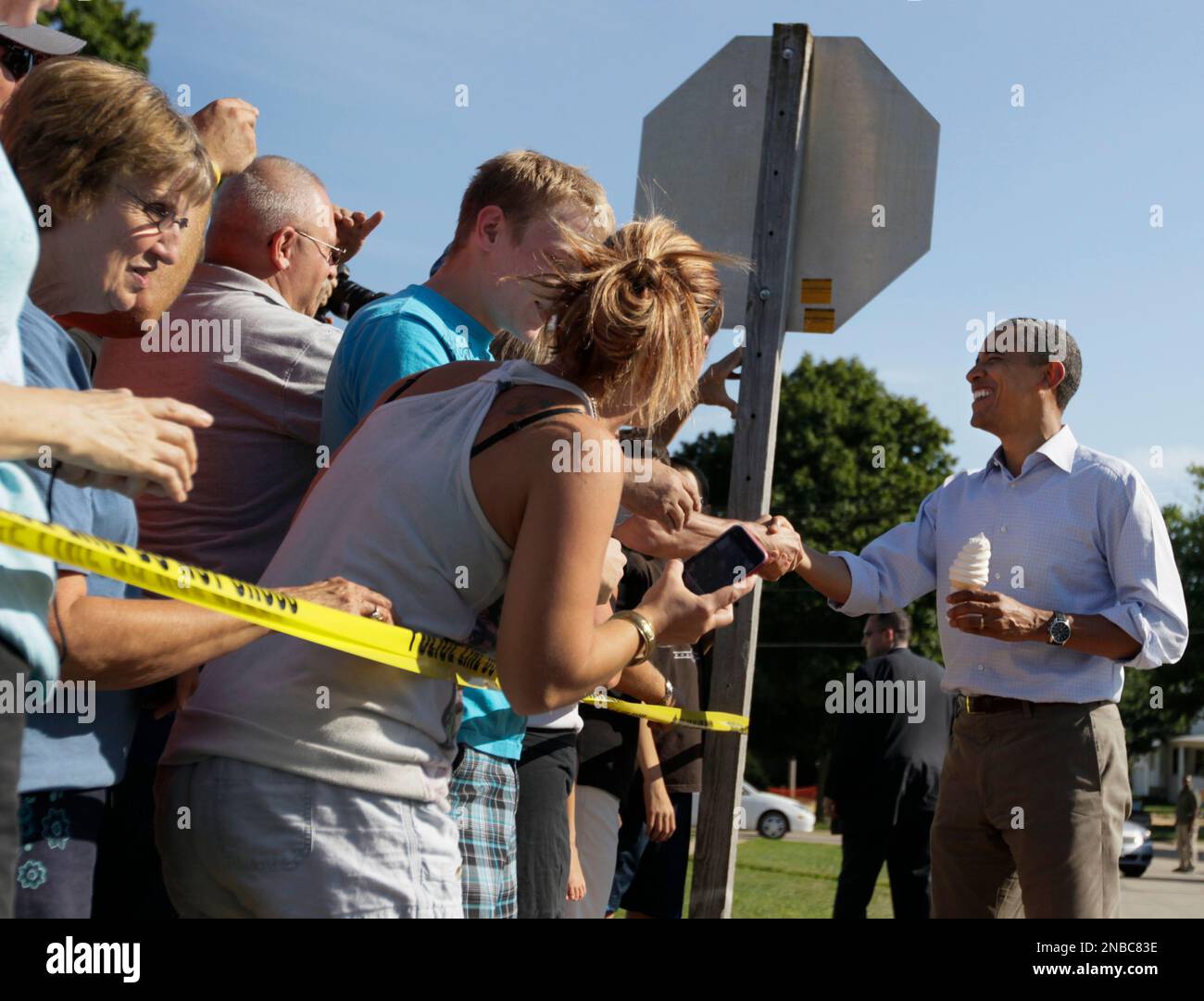 President Barack Obama, holding a soft serve ice cream cone, shakes ...