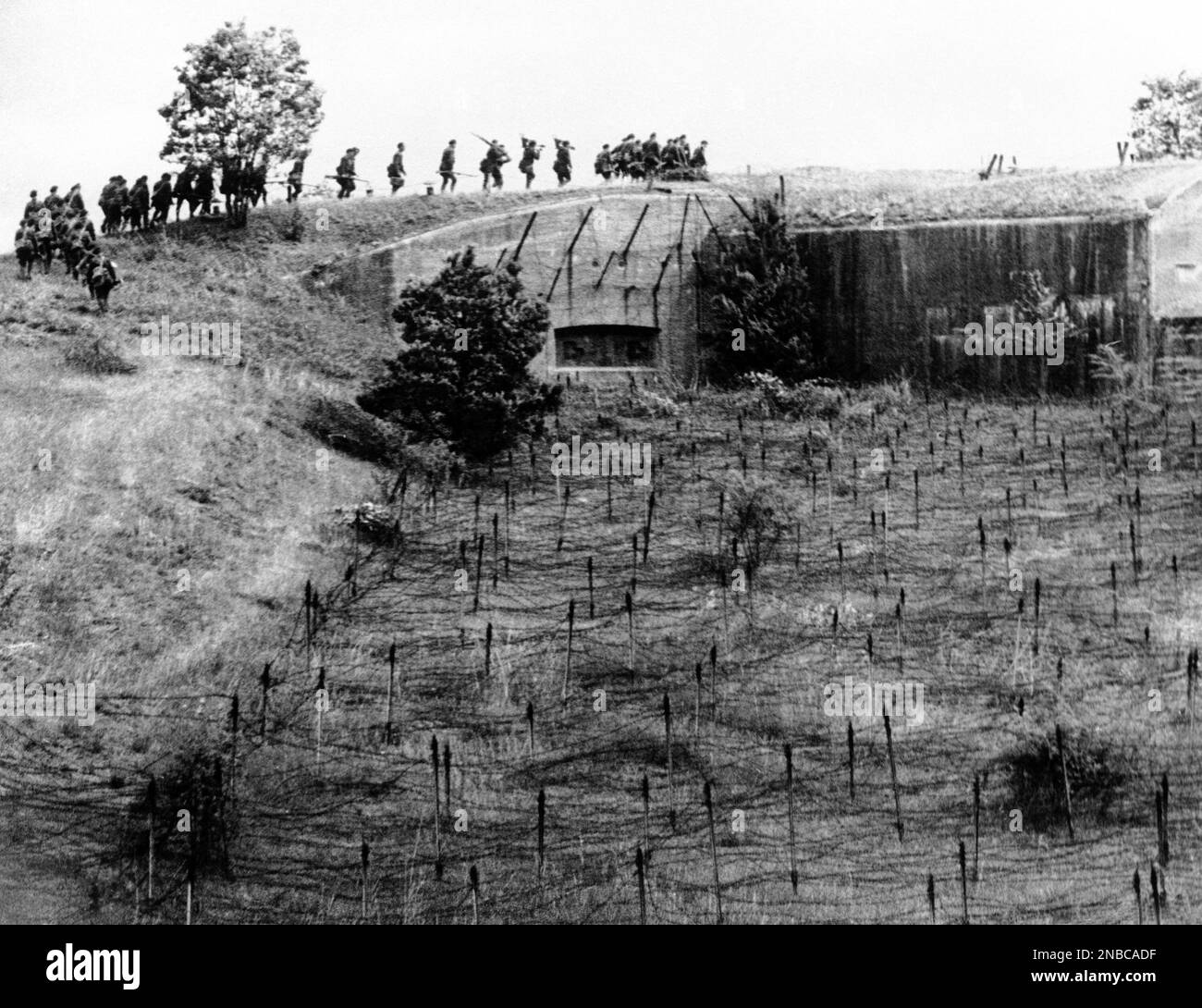 Through barbed wire strung on metal stakes the French troops march up ...