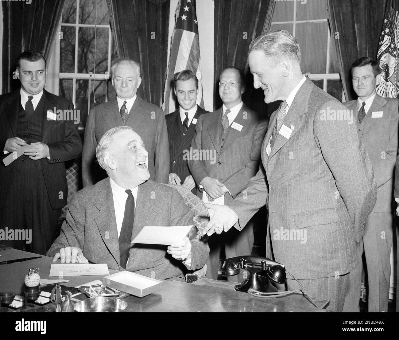 President Franklin D. Roosevelt laughs delightedly as he presents to ...