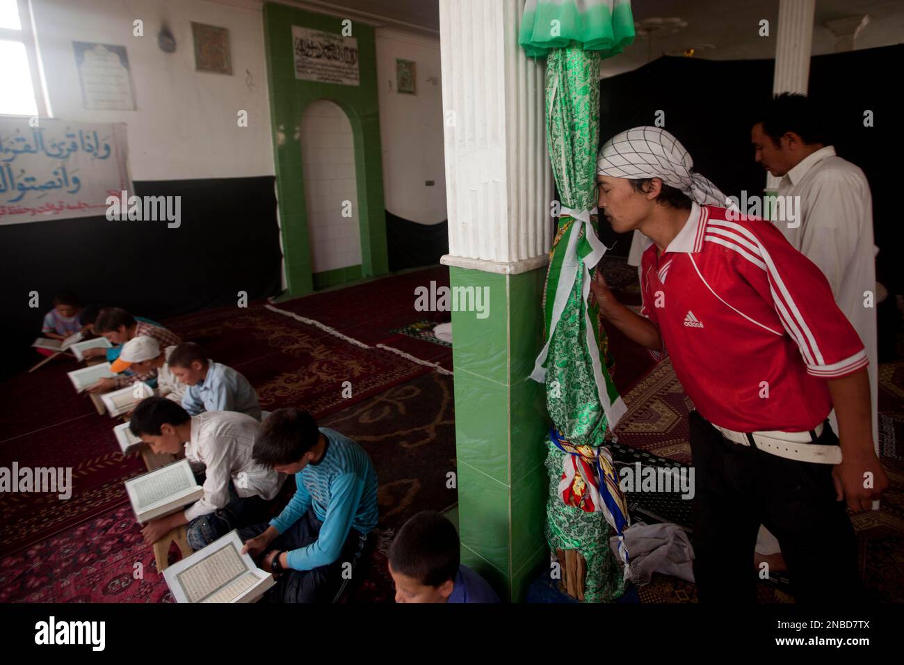 Afghan boy right, kisses a hole mace as other recite verses of the ...