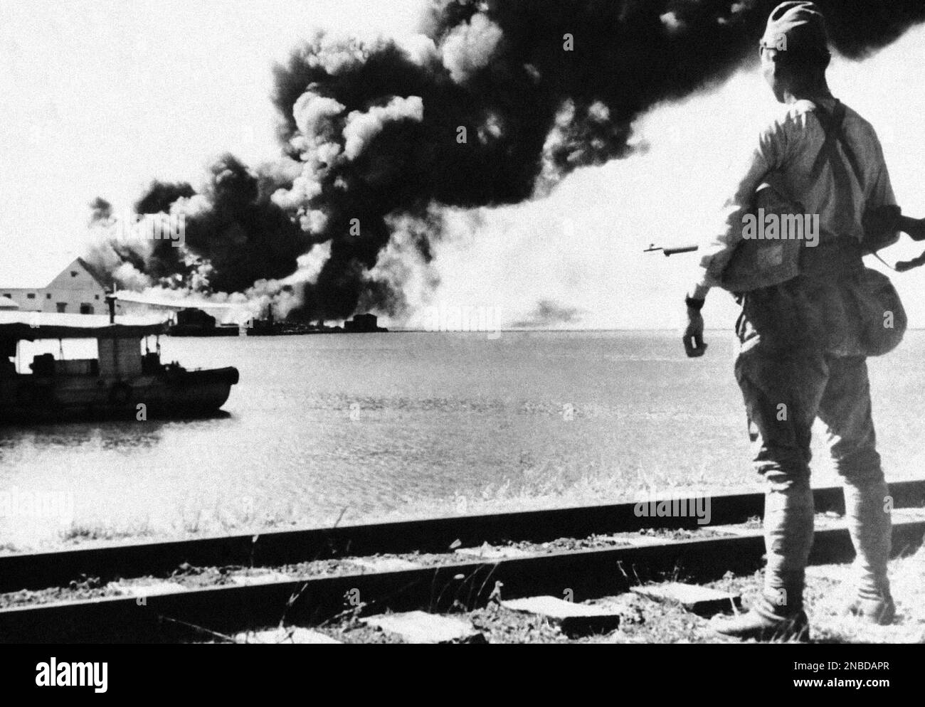 A Japanese soldier views the destruction of American oil supplies at ...