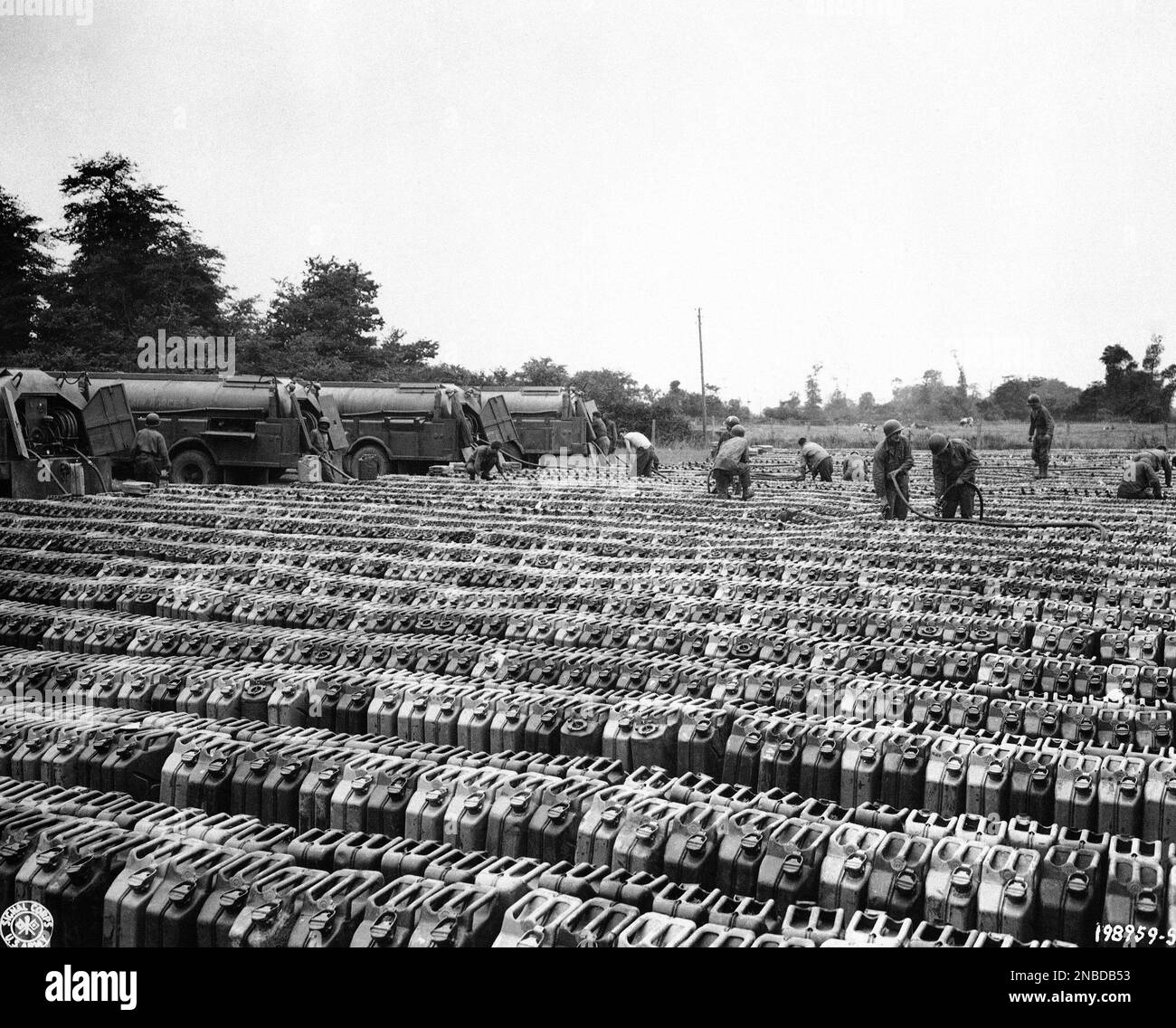 Large tank trucks are backed up to a field full of portable gas tanks ...
