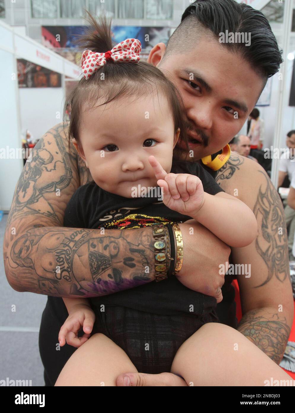 Taiwanese Paul holds his daughter and displays his tattoos at the ...