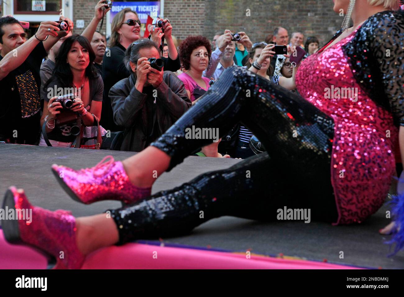 Spectators crowd around transvestites as they pose for pictures on a ...