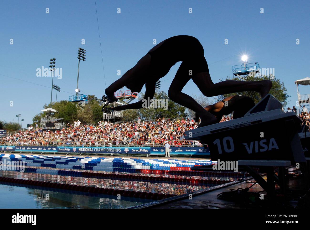 Margot Greer, foreground, jumps off the block as she competes in the ...