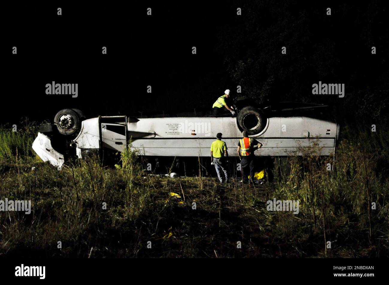 Rescue crews work to investigate an overturned tour bus alongside ...