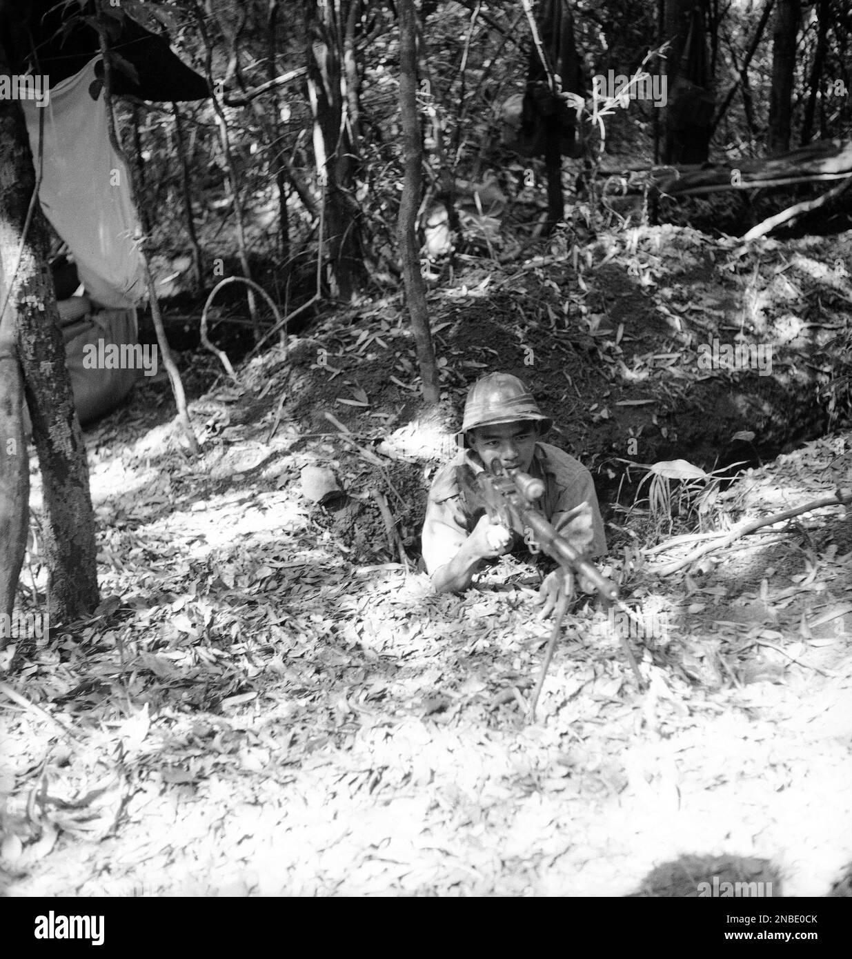 Filipino soldier shows how Japanese fire from foxholes with a captured ...