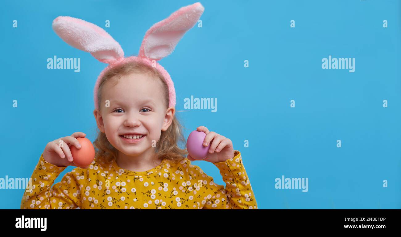 Cute happy little girl with bunny ears and holding colorful easter eggs ...