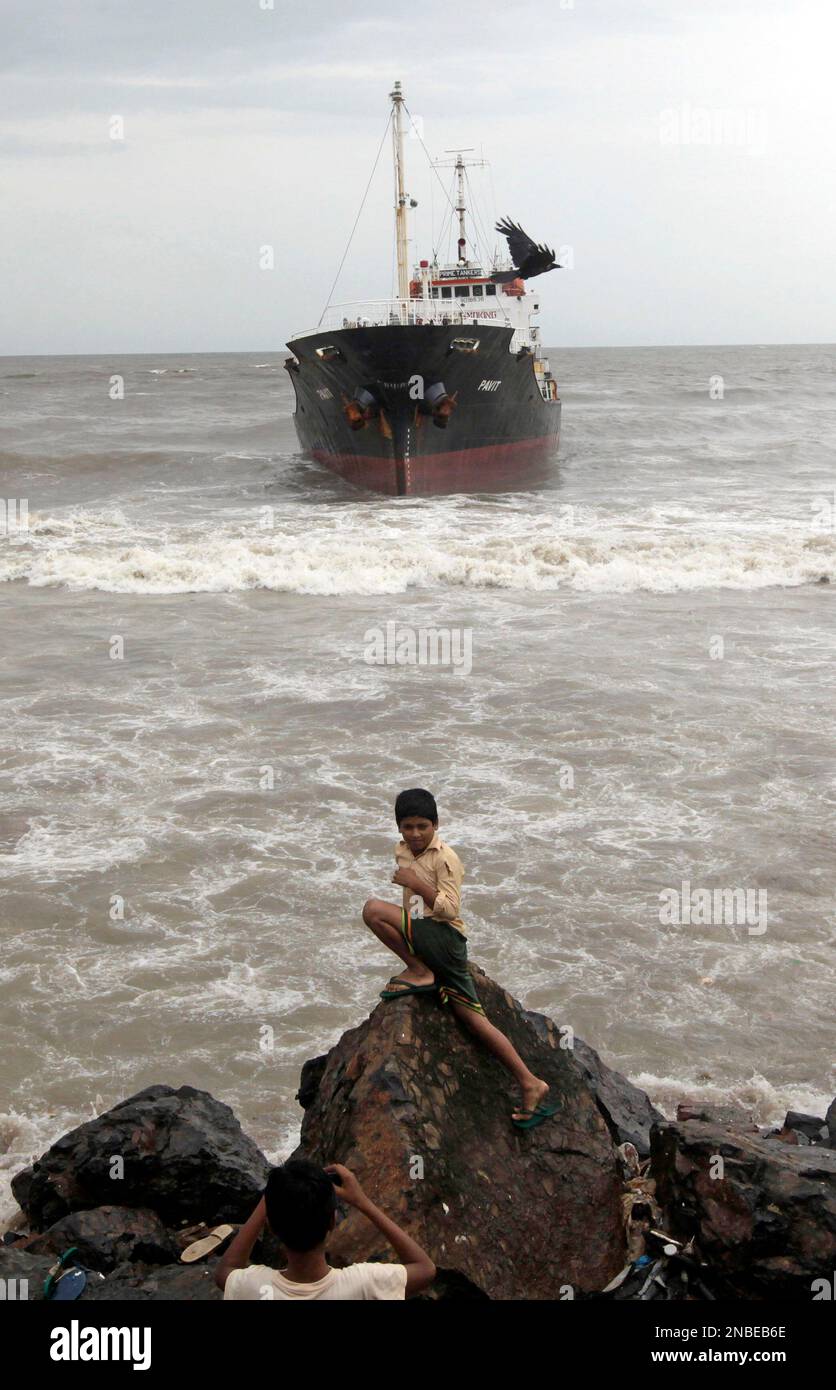 An Indian boy sitting on a rock gets photographed before a backdrop of ...