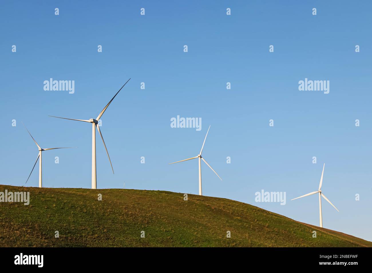 Wind power turbines on the green hill over the blue sky. Sustainable ...