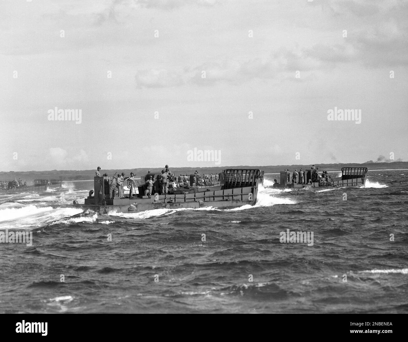 Tank lighters bearing troops and tanks head toward the beach. These are ...