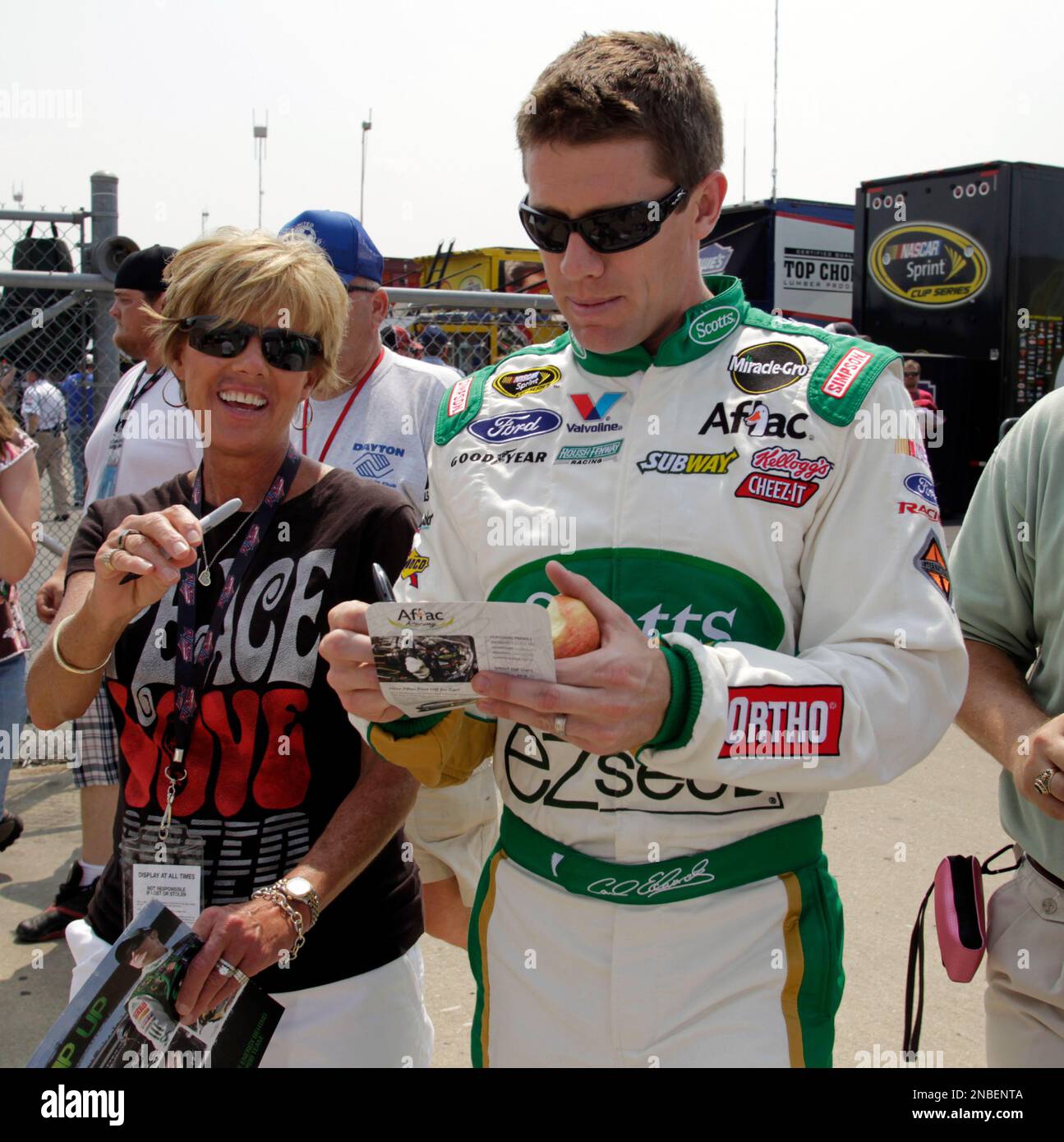 Carl Edwards signs a autograph for a fan as he walks to the garage area ...