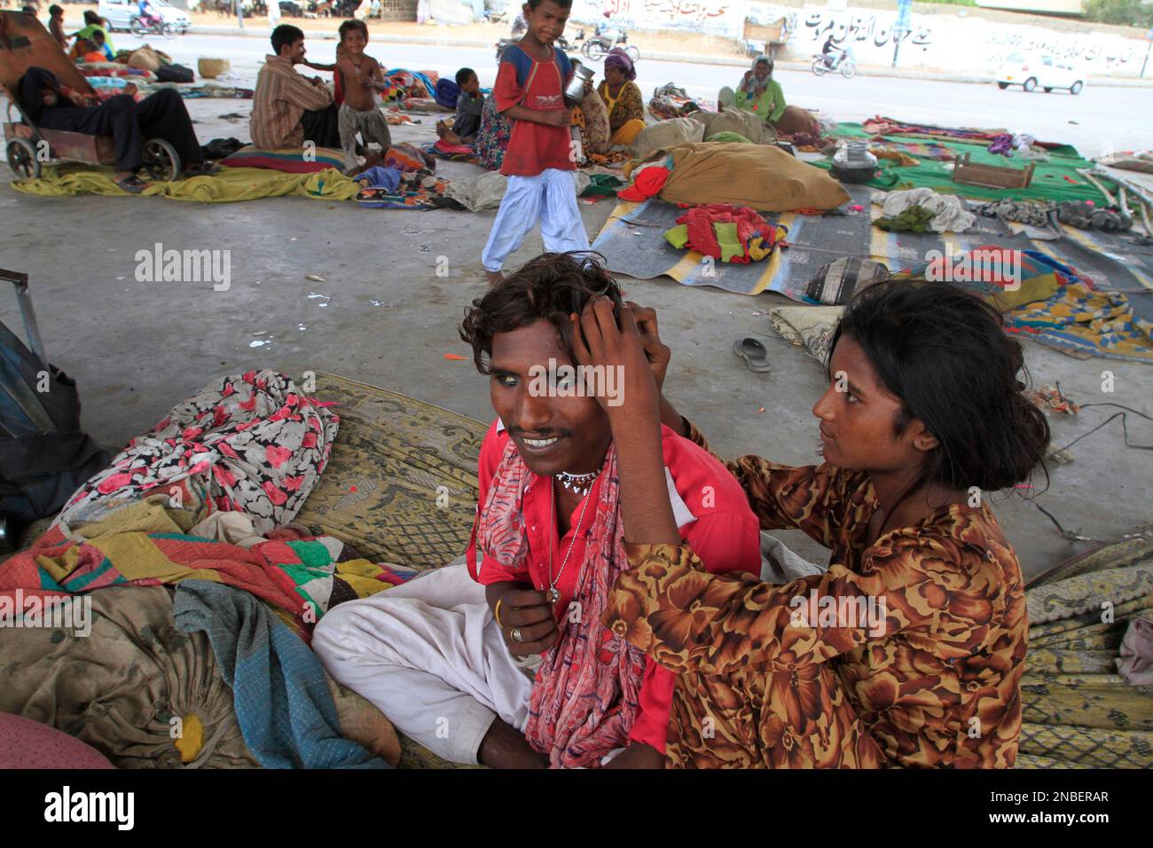 A homeless Pakistani woman checks the ear of a family member at their ...