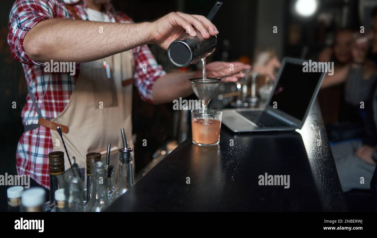 male bartender pouring a cocktail from a shaker. best service Stock Photo - Alamy
