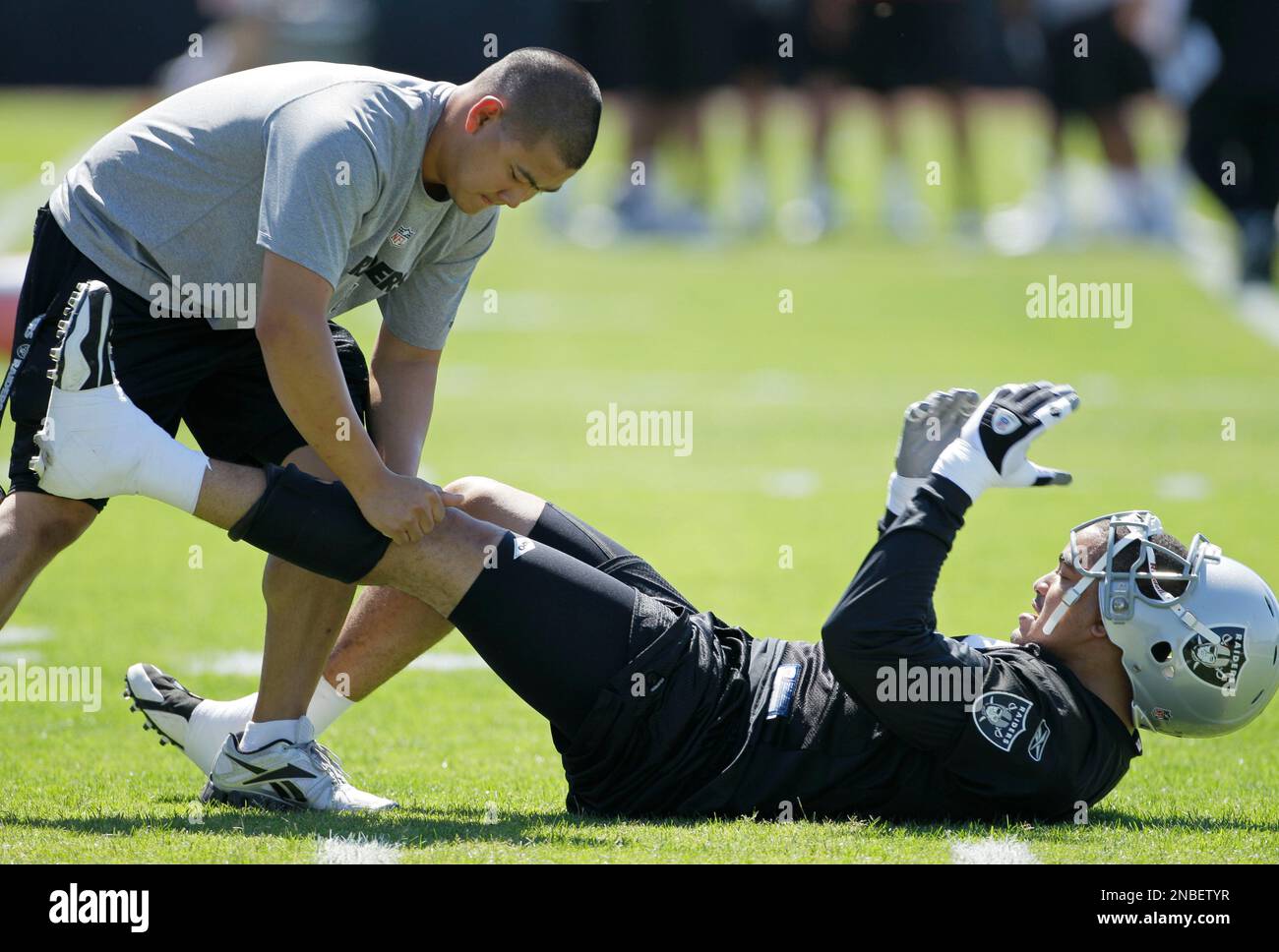 Oakland Raiders defensive end Matt Shaughnessy, right, is stretched ...