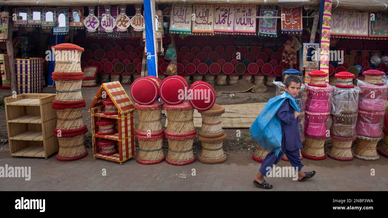 A Pakistani boy who scavenges to survive walks past a stall displaying ...