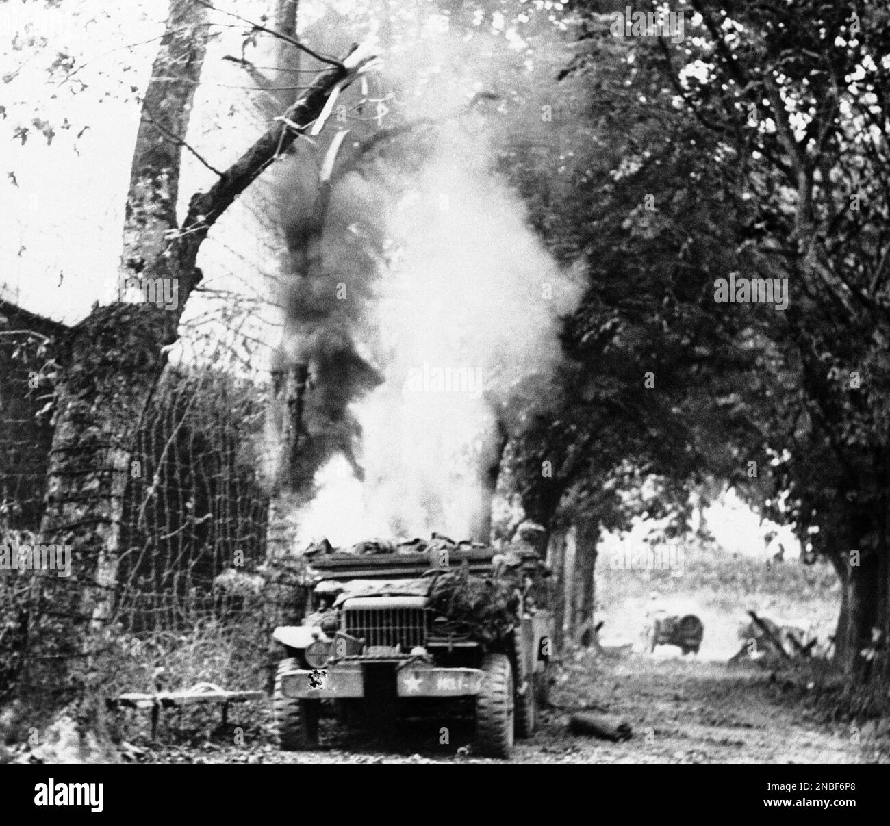 A half-track vehicle burns alongside a count road near St. Lo, France ...