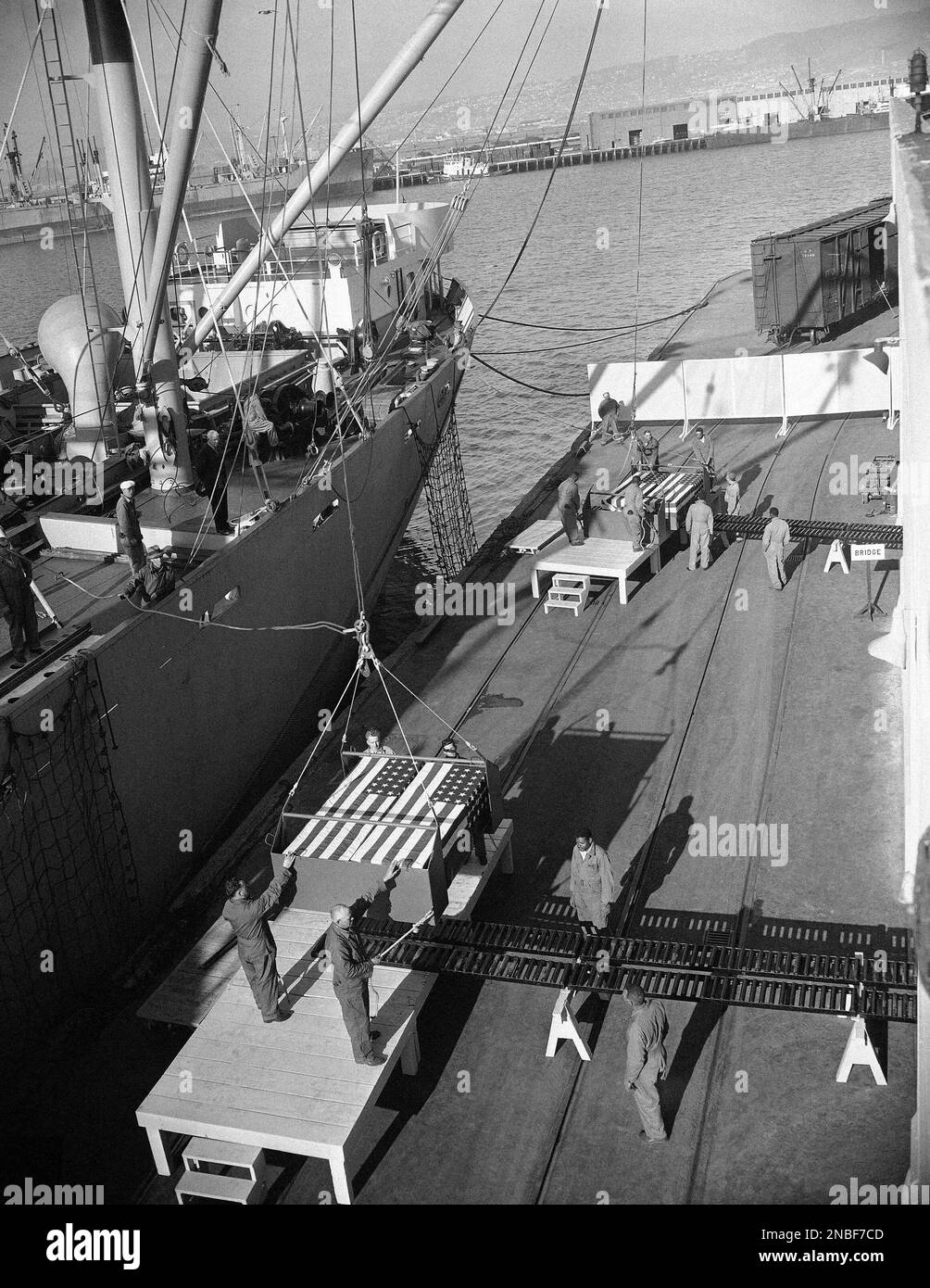 Flag draped caskets taken from holds of funeral ship, USAT Cardinal O ...