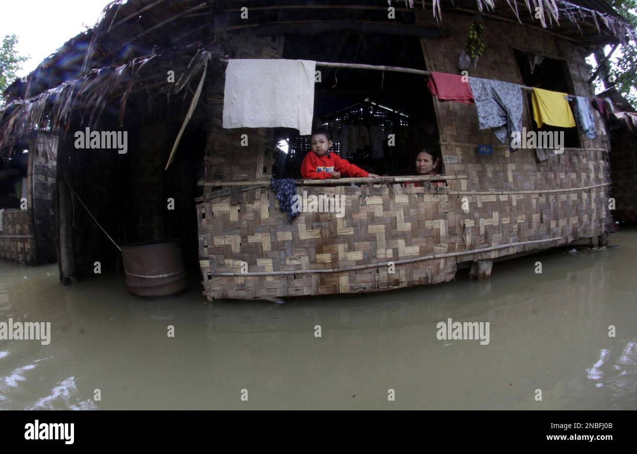 Residents stay inside a house half-submerged in floodwaters in a low ...