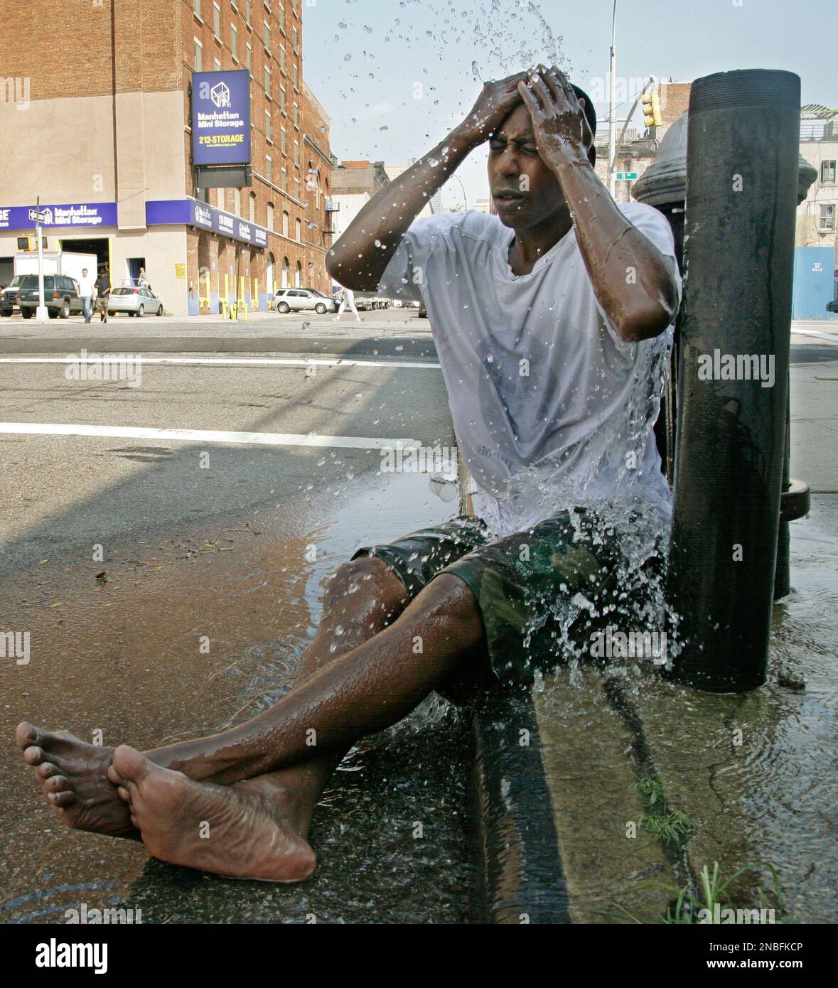 Shon Oliver takes a seat in an open fire hydrant to get some relief ...