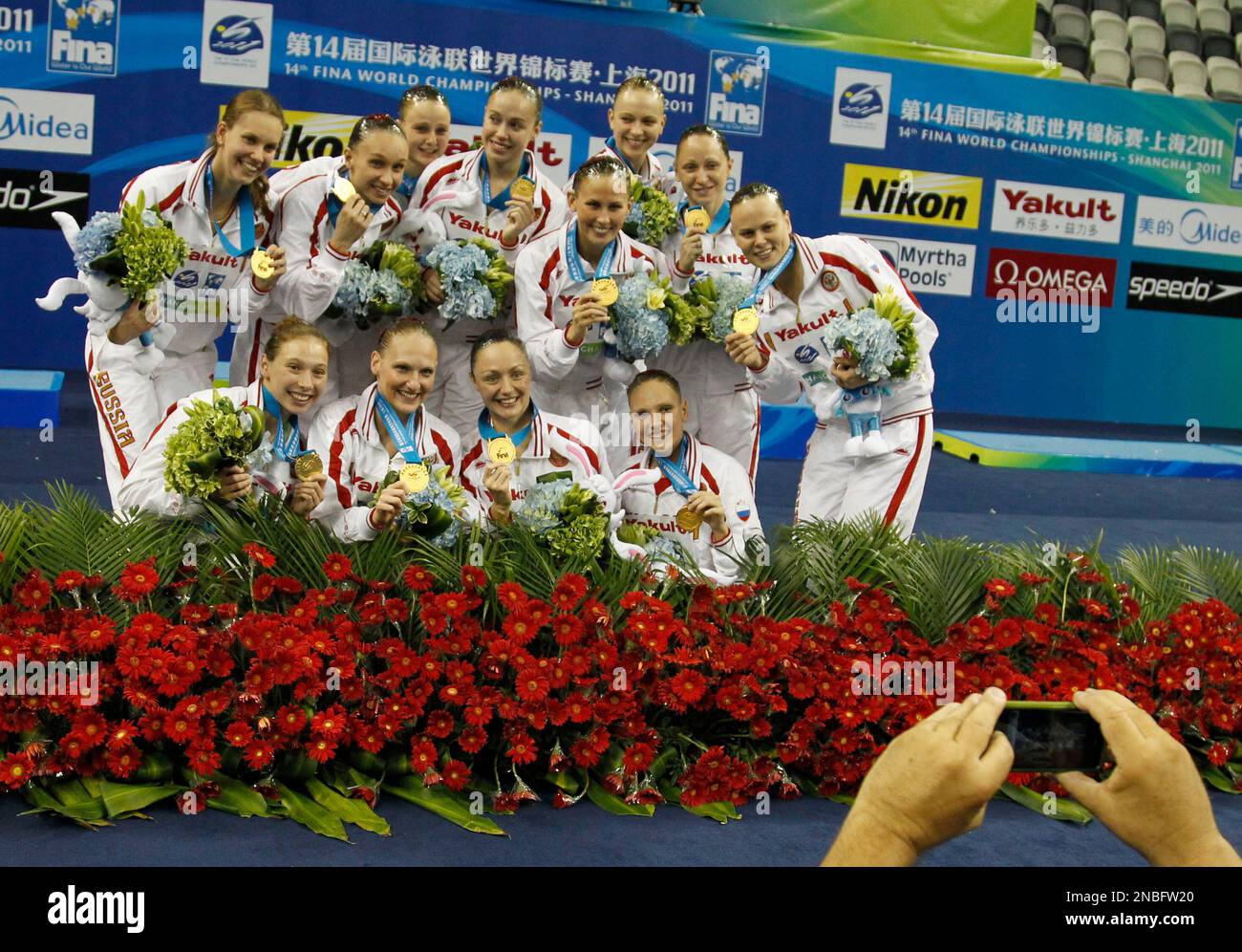 A man takes a picture of the Russian team posing with the gold medals ...