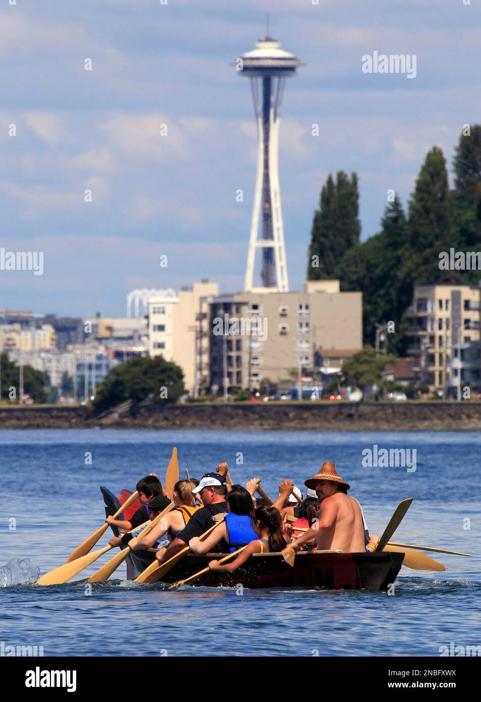 A tribal canoe, in view of the Space Needle, is maneuvered into ...