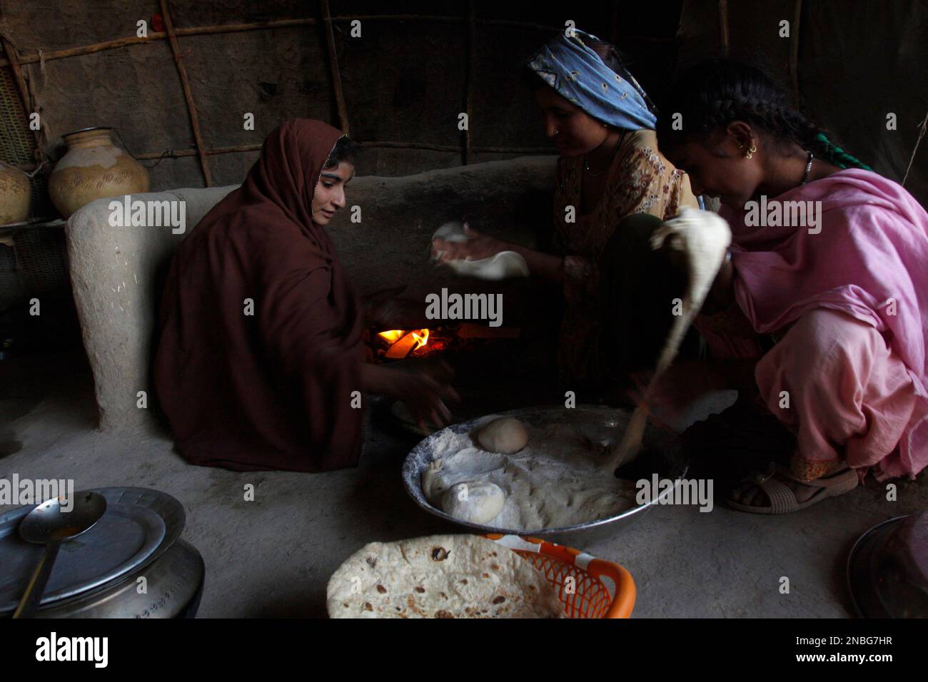 Pakistani girls prepare bread in their make-shift kitchen living in the ...