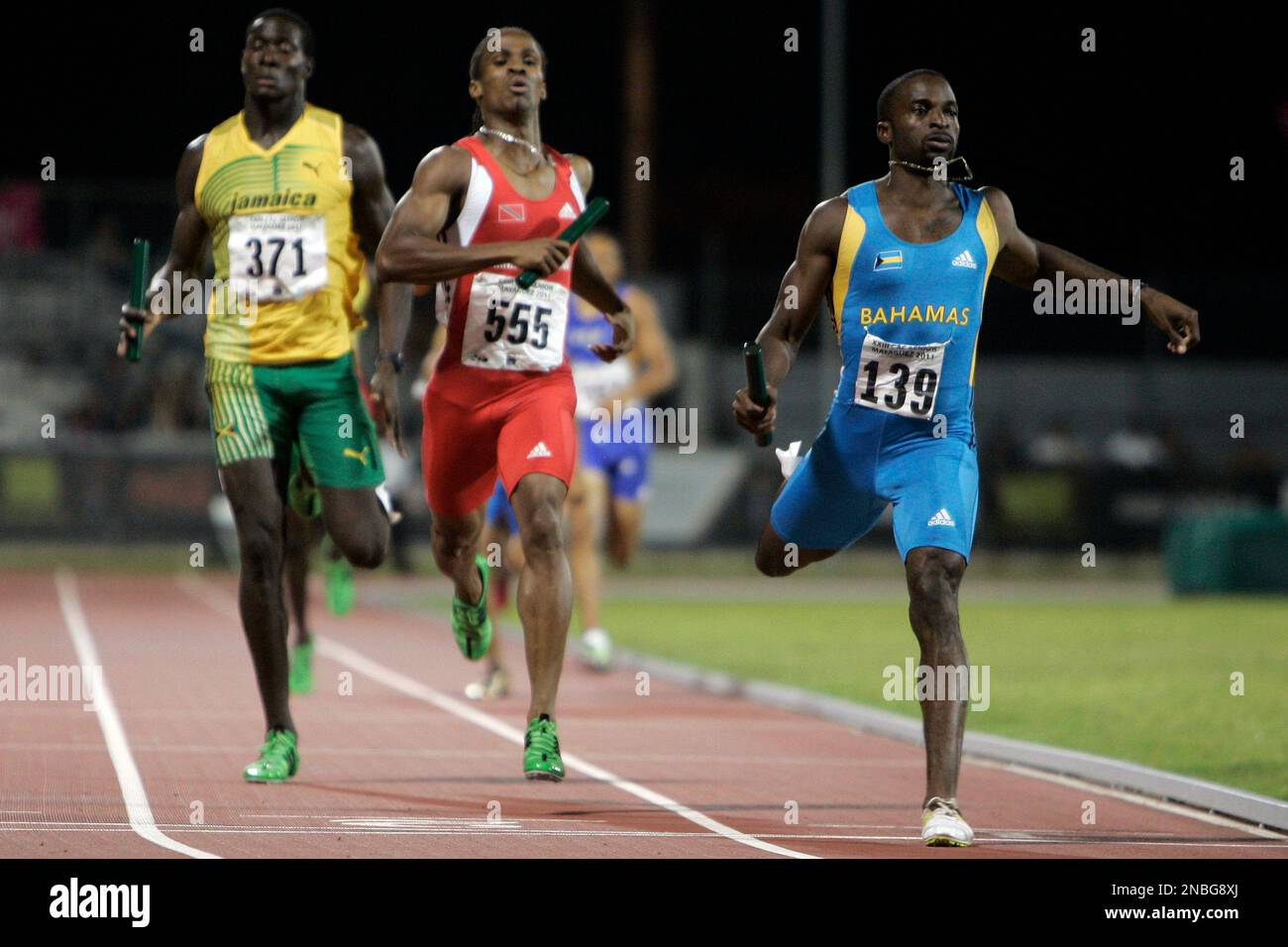 Bahamas' Ramon Miller, right, crosses the finish line in first place ...
