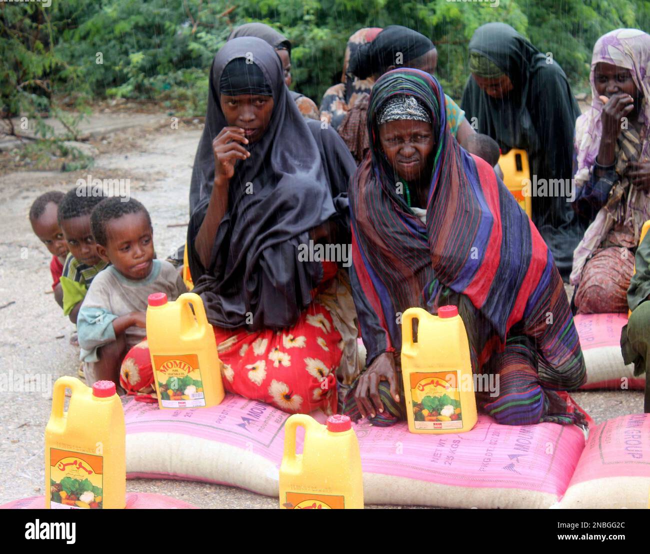 Somali women and children from southern Somalia wait in the rain with ...