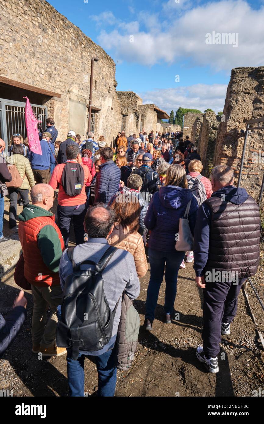Groups of tourists, visitors pack, crowd a typical small street area ...