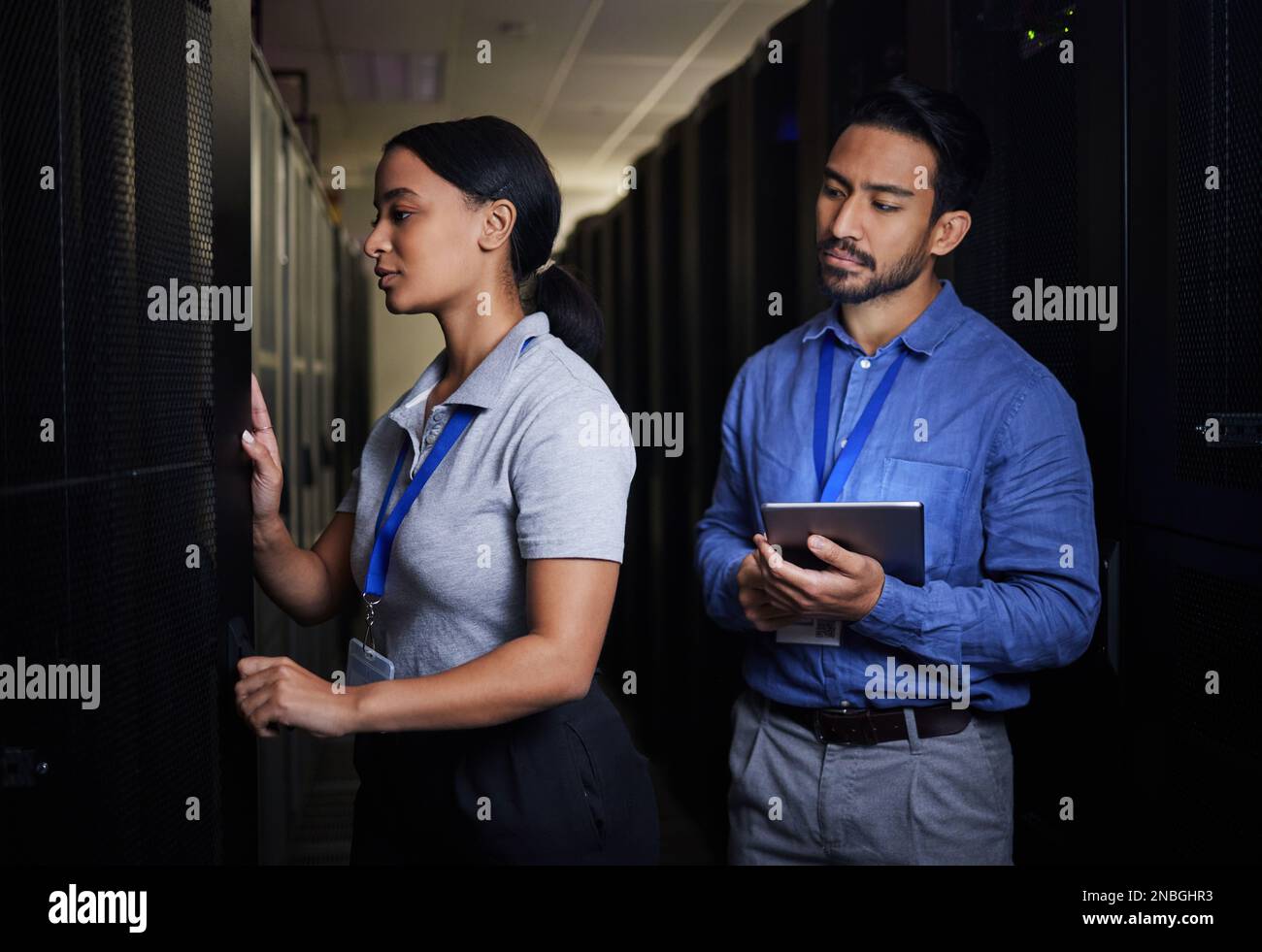 Engineer, server room teamwork and woman opening panel for maintenance or repairs at night ...