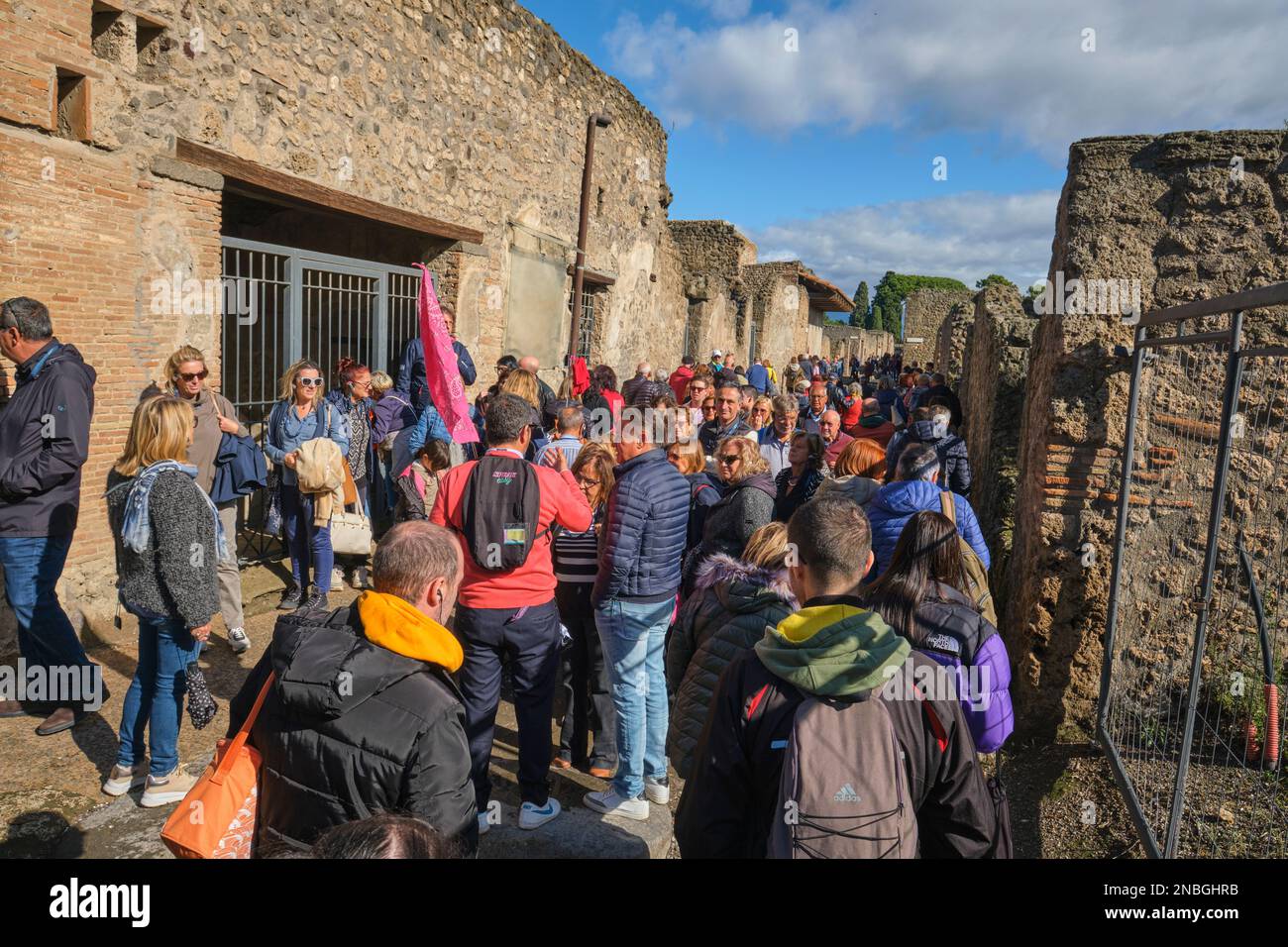 Groups of tourists, visitors pack, crowd a typical small street area ...