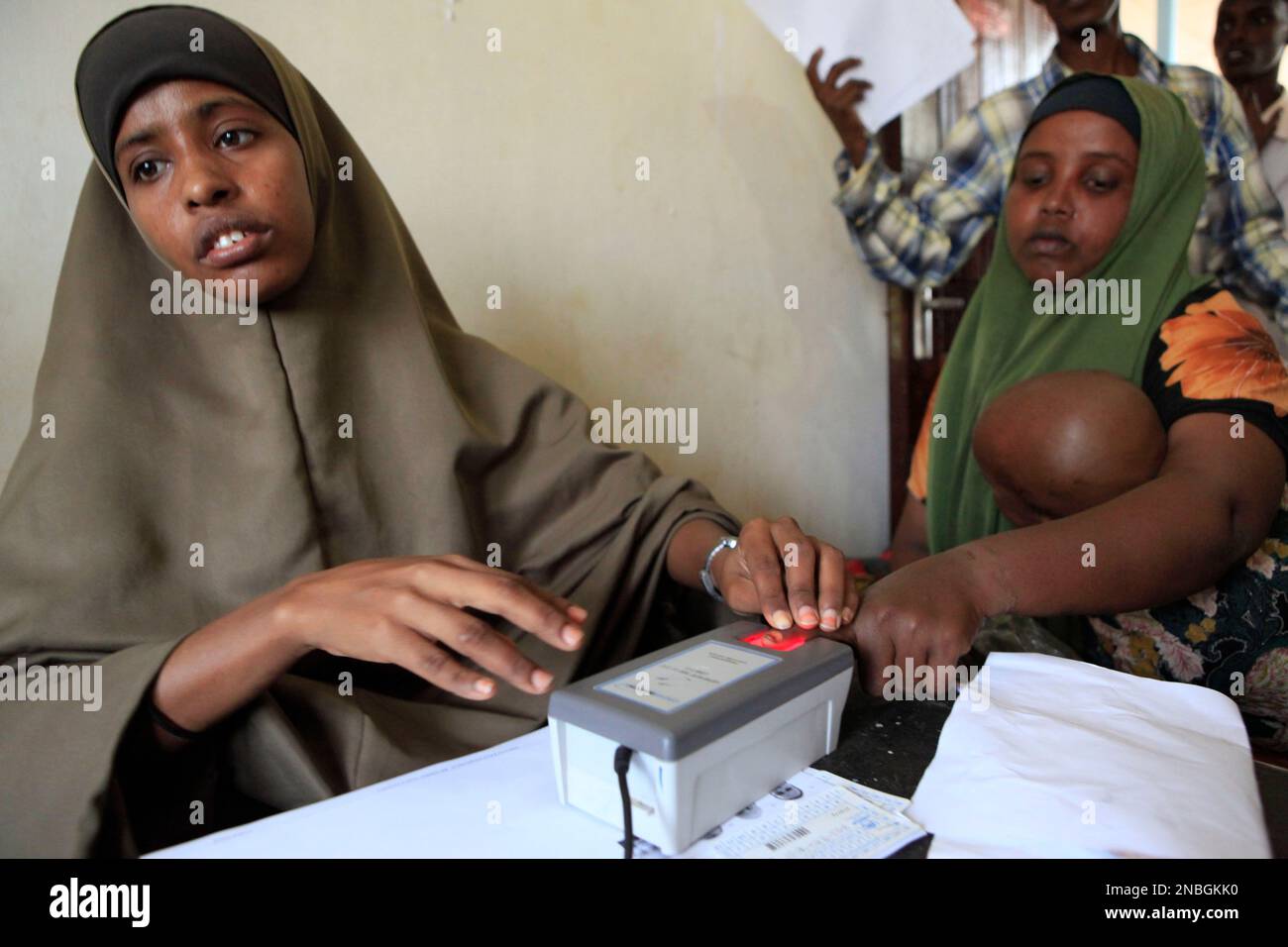 Somali worker Nimo Jama Said, left, takes the fingerprints of a newly ...