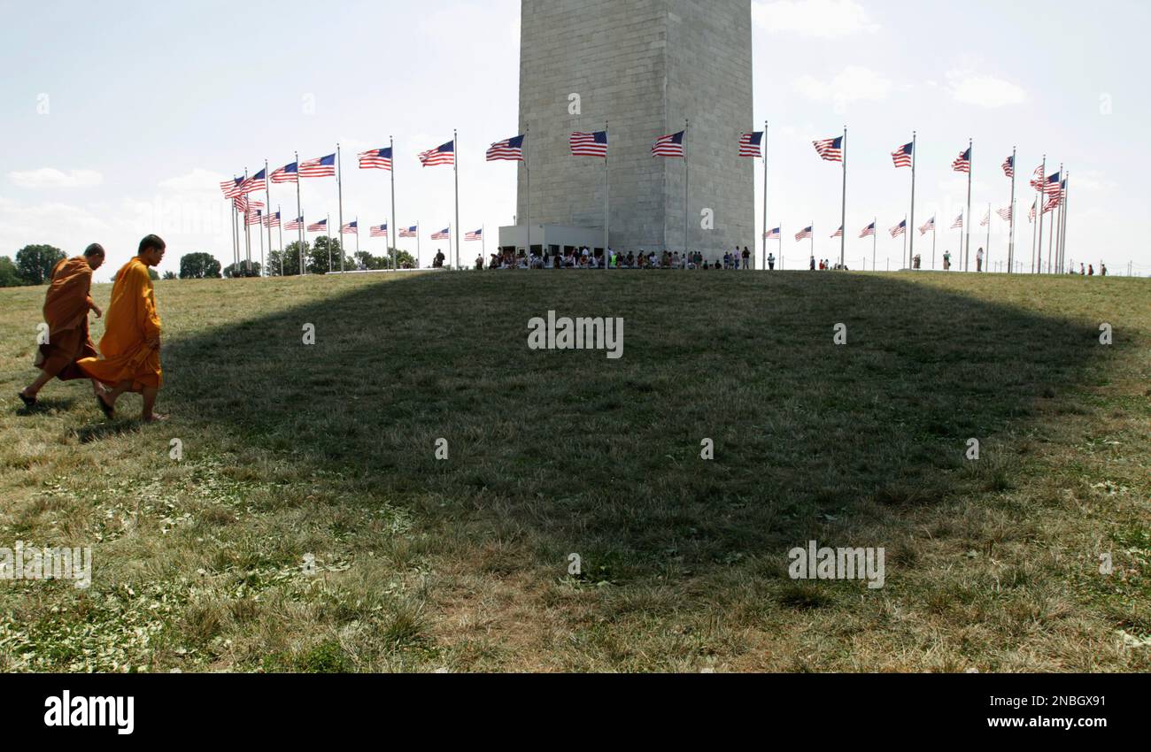 The Washington Monument casts a shadow and people take shelter from the ...