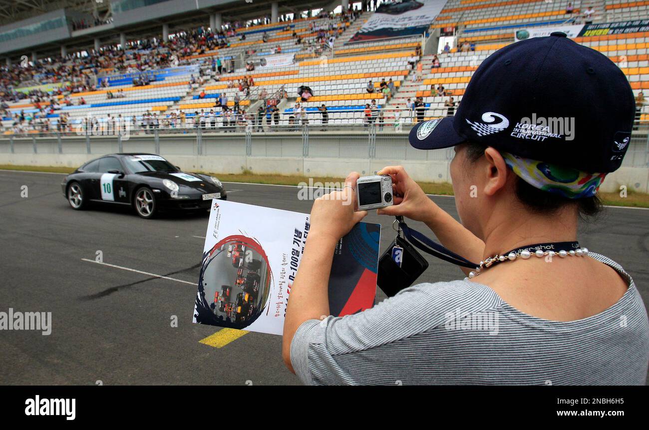A woman takes a picture of a racing car at Korea International Circuit ...