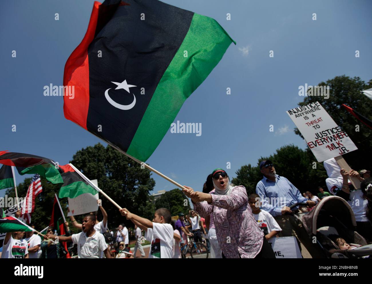 A woman, who does not want to be named, and other demonstrators wave ...