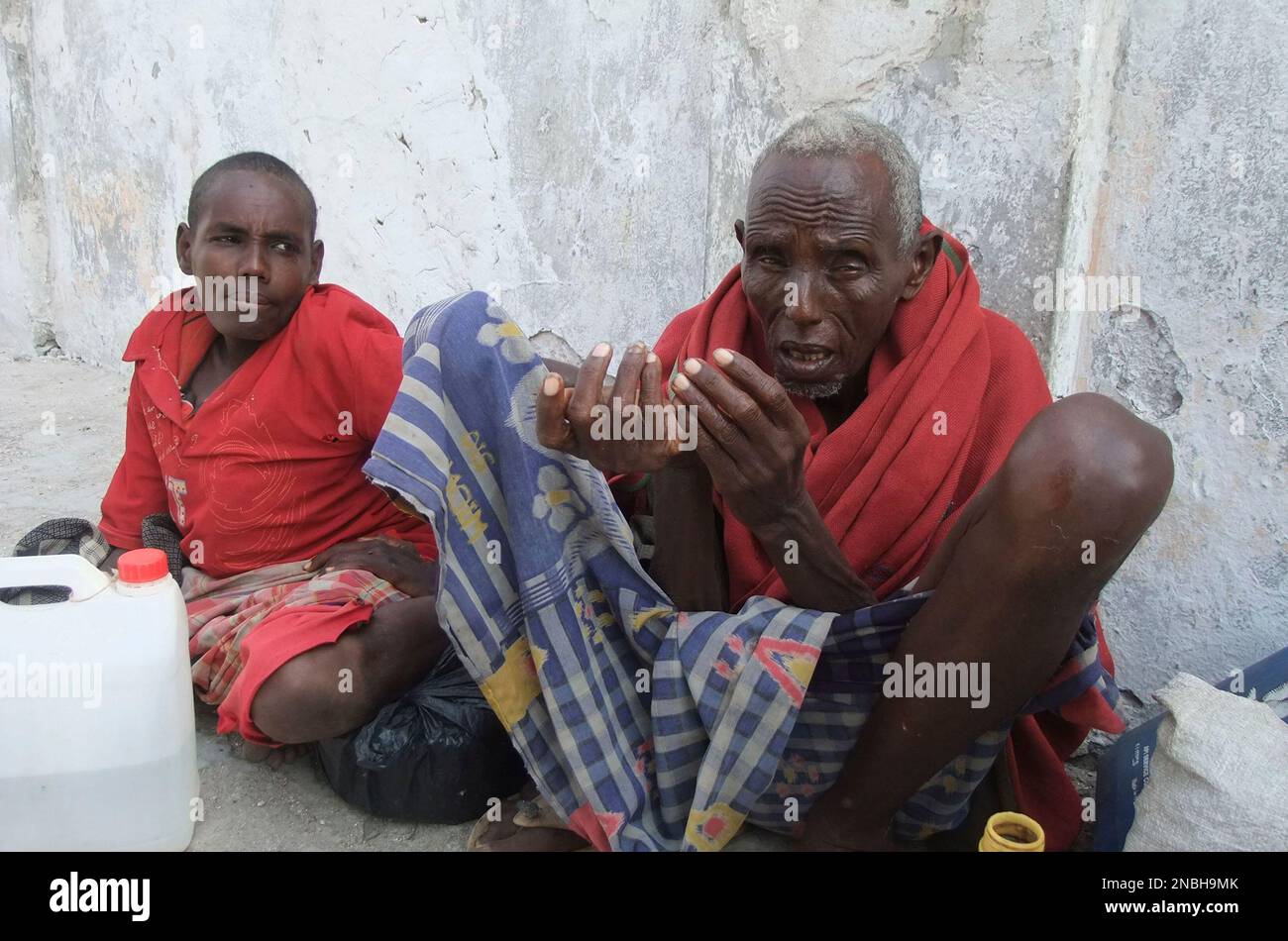 An old Somali man with his son from southern Somalia wait inside a ...